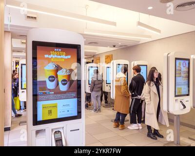 People ordering their fast food using touchscreen order terminals ...