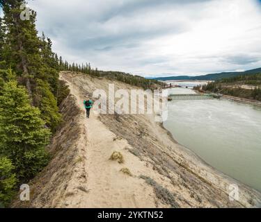 Woman hiking along the side of the Yukon River outside of Whitehorse in ...