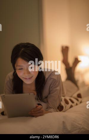 Woman operating tablet PC lying on bed Stock Photo - Alamy