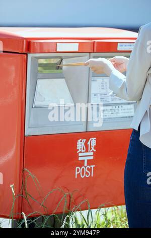 Young woman's hand putting an envelope in a mailbox Stock Photo - Alamy
