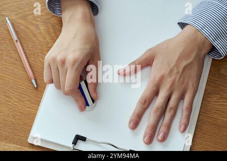 Woman erasing letters on a document with an eraser in her hand Stock ...