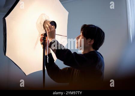A Japanese male photographer adjusting the strobe in a photography ...