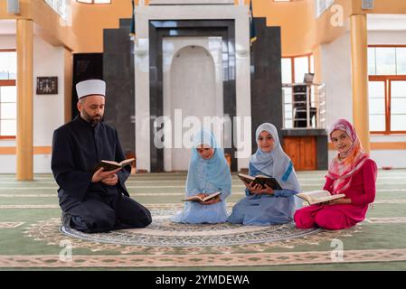 A Muslim teacher teaches children girls to read a holy book Quran ...