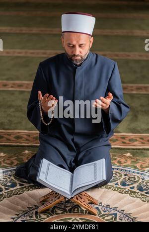 Praying Muslim man with Koran on dark background Stock Photo - Alamy