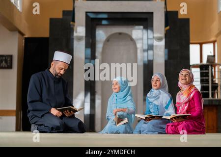 A Muslim teacher teaches children girls to read a holy book Quran ...