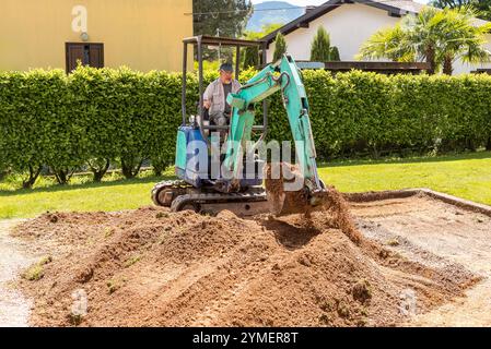 An earthmoving worker digging ground at construction site with crawler ...