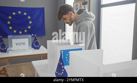 Young hispanic man at political election sitting by ballot smiling with ...