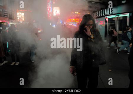 People walk past steam coming out from the ground on the street in ...