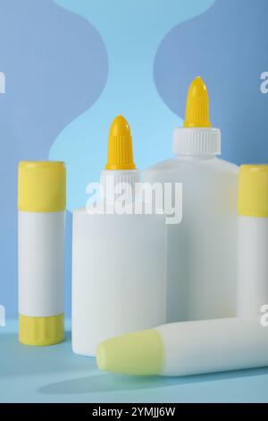 Different types of glue and paper cutouts on light blue background ...