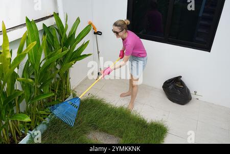 A woman raking the lawn at the backyard of her house Stock Photo - Alamy