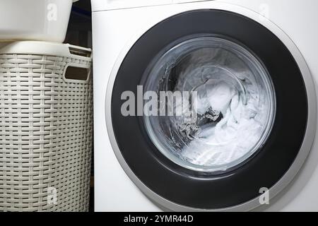 Washing machine with clothes and suds near laundry basket Stock Photo ...