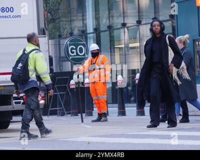 Banksman with go traffic sign directing pedestrians and traffic at ...