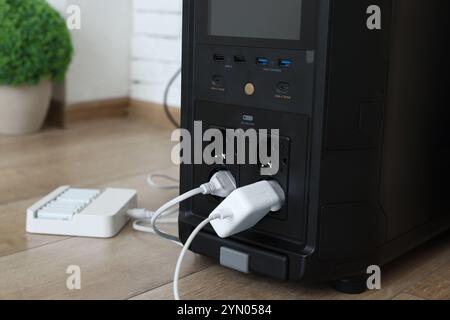 Modern portable power station with attached device indoors, closeup ...