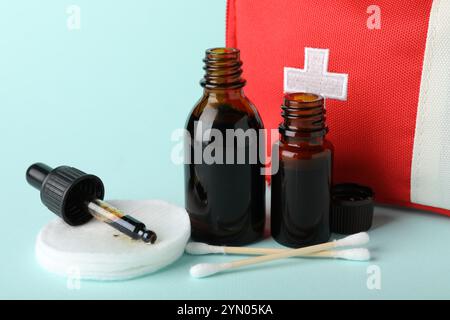 Topical iodine and other first aid kit components on light blue ...