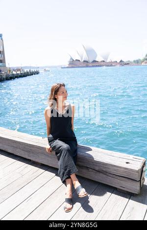 Woman sitting with opera house in background Stock Photo - Alamy