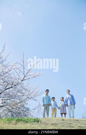 Happy family standing under a cherry tree Stock Photo - Alamy