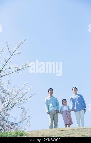 Happy family standing under a cherry tree Stock Photo - Alamy