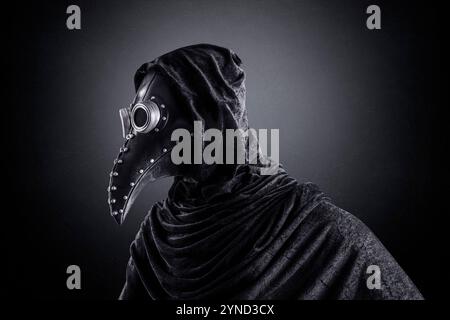 Plague doctor in hooded cloak at night over dark misty background Stock ...