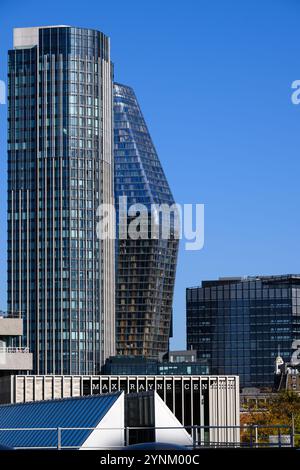 Tall residential buildings rise behind a field of greenery under a gray ...