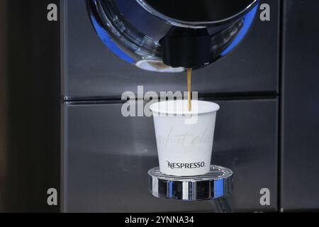 Fresh espresso dripping into a Nespresso-branded paper cup Stock Photo ...