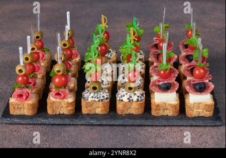 Assortment of canapes with cherry tomatoes, sausage, cheese, olives and ...