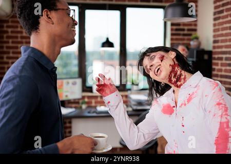 Cheerful man dressed as a scary zombie poses over a black background ...