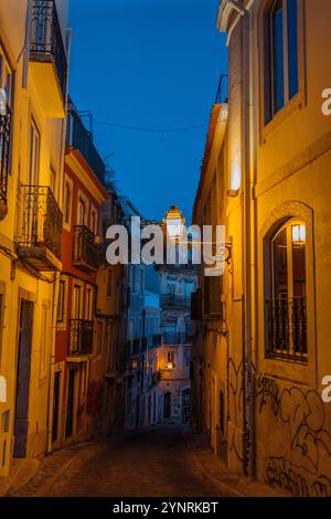 A narrow city street illuminated by vibrant colorful light projections ...