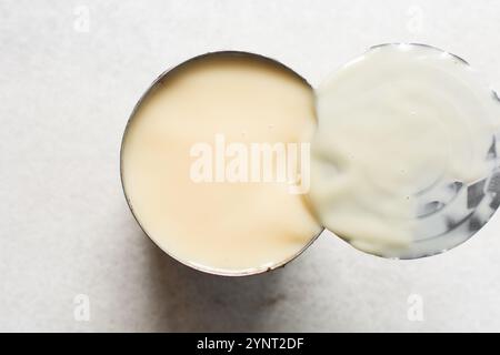 Overhead view of an opened tin of condensed milk with the lid, top view ...