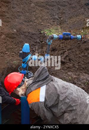 Workers install a water intake unit in a well. Installation of the ...