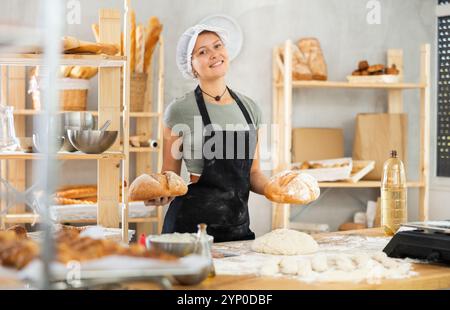 Bakery woman employee holds ready made bread of bread Stock Photo - Alamy