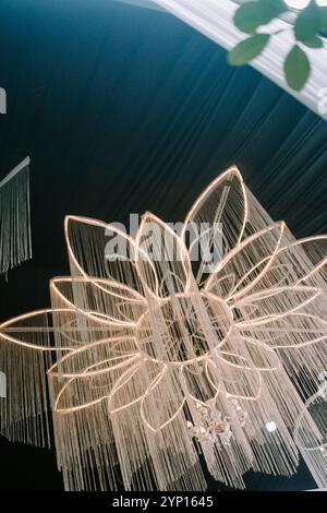 An elegant floral-shaped chandelier with glowing string lights and ...