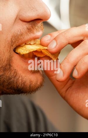 Bearded man bites golden potato chips. Perfect for food and lifestyle ...