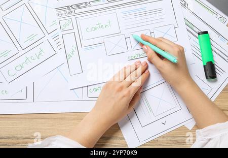 Website designer creating wireframe on paper with pen at wooden table ...
