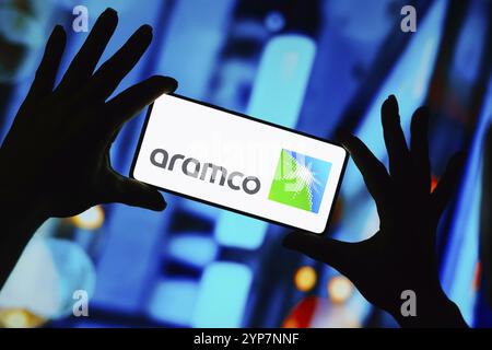 The Aramco logo displayed on a phone screen against a world map and ...