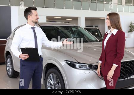 Salesman and client near new car in salon Stock Photo - Alamy