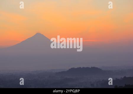 Silhouette of Mount Merapi with a red-orange sky at sunrise. The ...