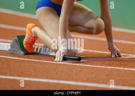 Runner preparing at starting blocks for a relay race during a track ...