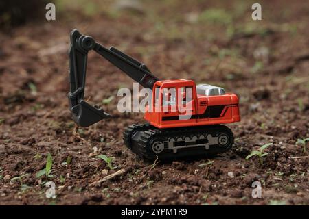 Orange excavator or digger toy excavate on a soil land outdoor. model ...
