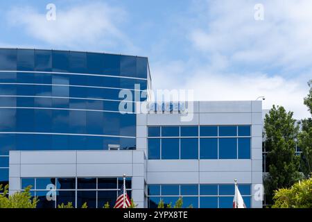 Exterior of Amgen office building with blue logo on modern glass facade ...