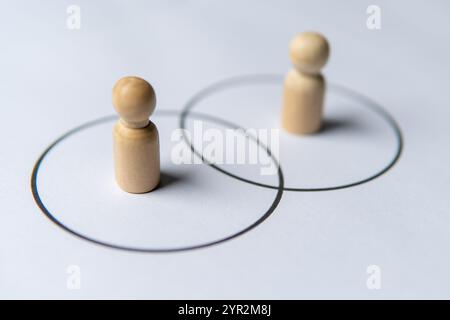 Two wooden figures standing in separate circles overlaps with each ...