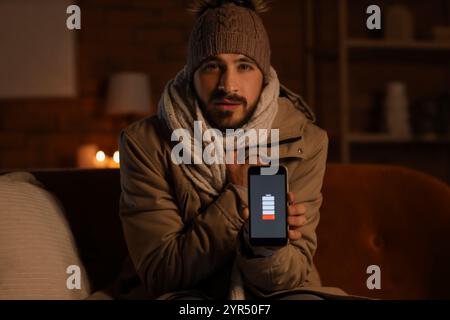 Young man with discharged mobile phone in office during blackout ...