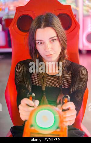 A focused gamer girl engages in an exhilarating arcade shooting game ...