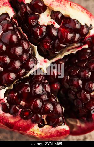 Vibrant red pomegranate cut open to reveal juicy seeds beside whole ...