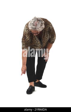 senior woman crouching and pointing finger at the ground on white ...