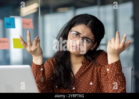Puzzled woman staring at the camera and thinking with hand on chin ...