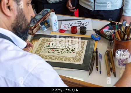 Male Arab calligraphist writing an Arabic name for a customer in Arabic ...