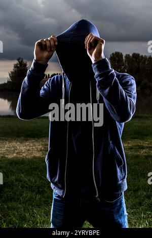 Mysterious hooded man covering his face with a hoodie in a dramatic ...