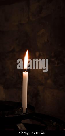 Candle in church (against rough stone wall background). Light and ...
