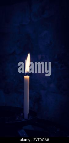 Candle in church (against rough stone wall background). Toned photo ...