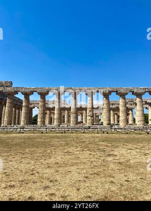 Ancient Doric temple at Paestum framed by trees, with mountains in the ...